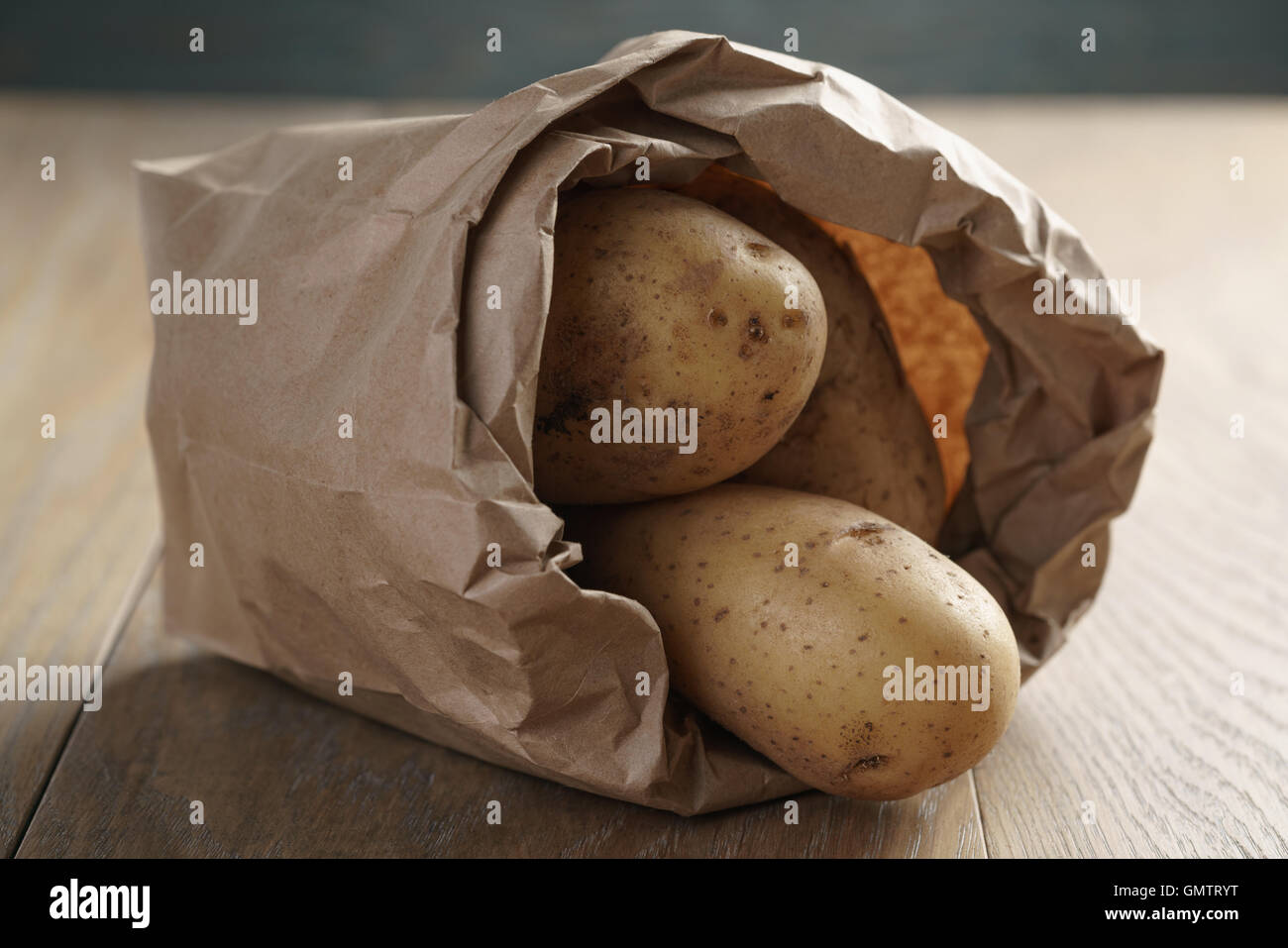 fresh potatoes in kraft paper bag on oak table Stock Photo - Alamy