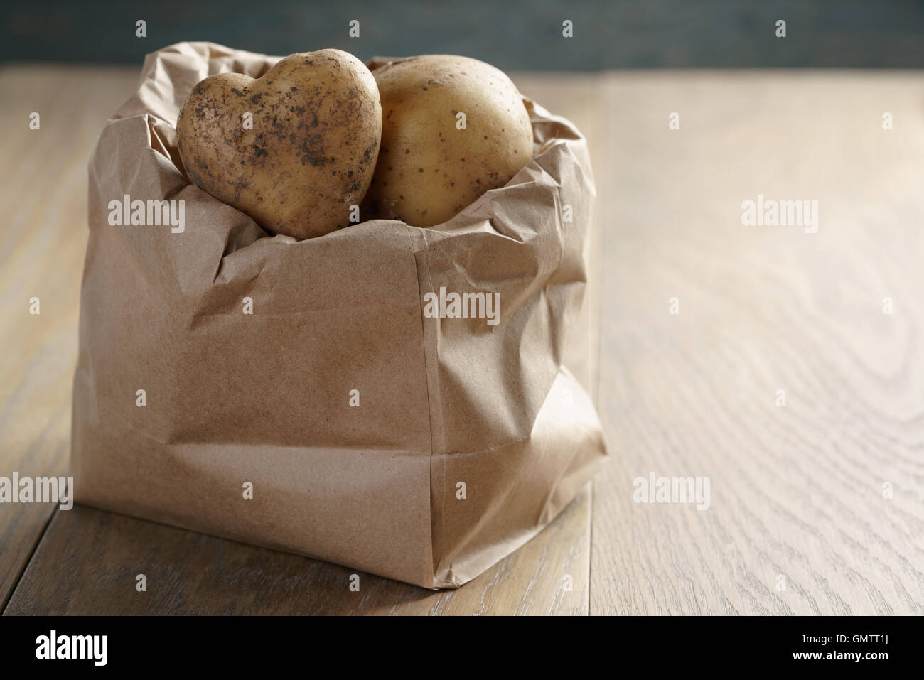 fresh potatoes in kraft paper bag on oak table Stock Photo - Alamy