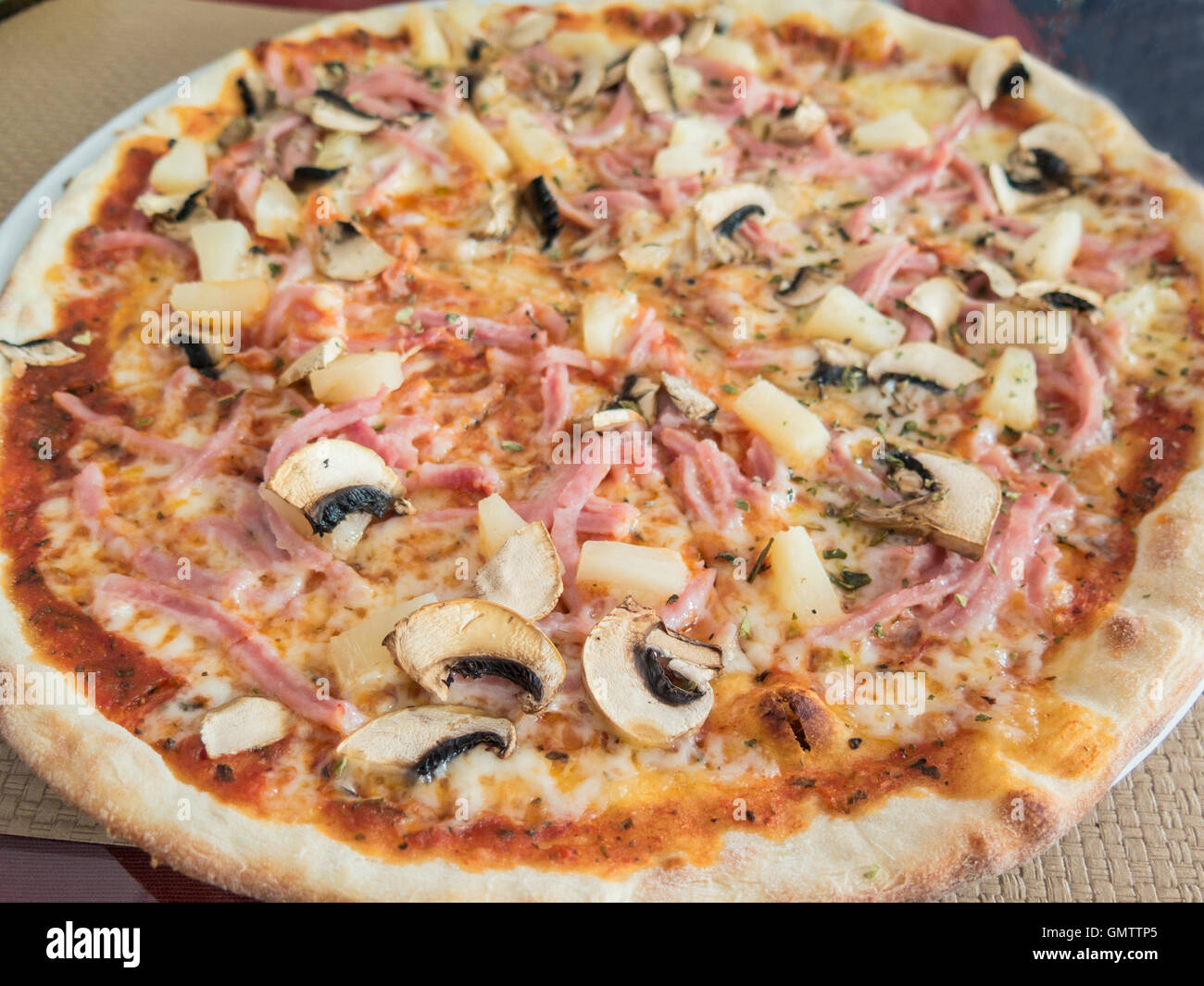 A round pizza with ham, pineapple and mushroom topping Stock Photo - Alamy
