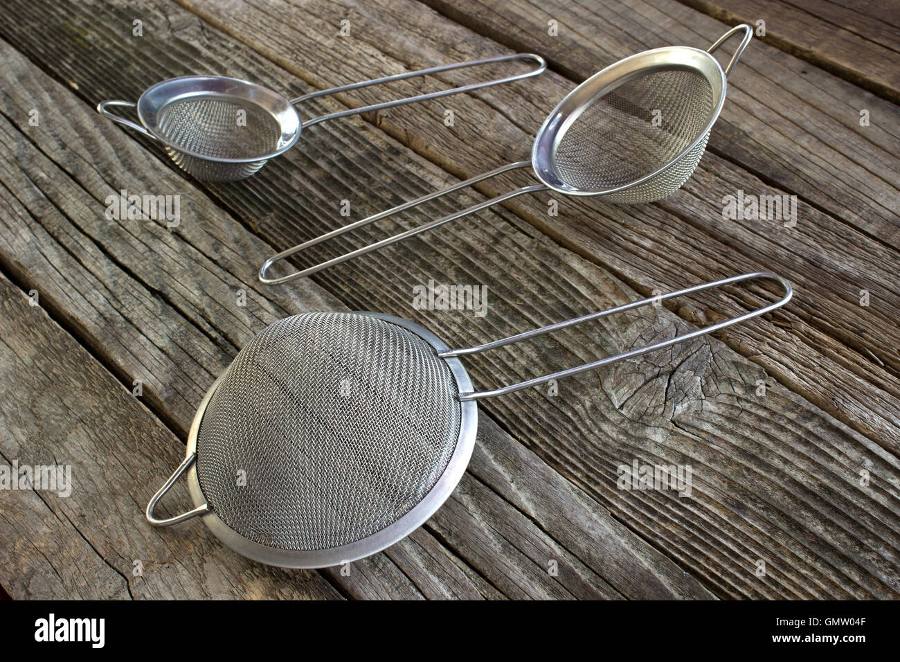 Three colanders on wooden background Stock Photo - Alamy