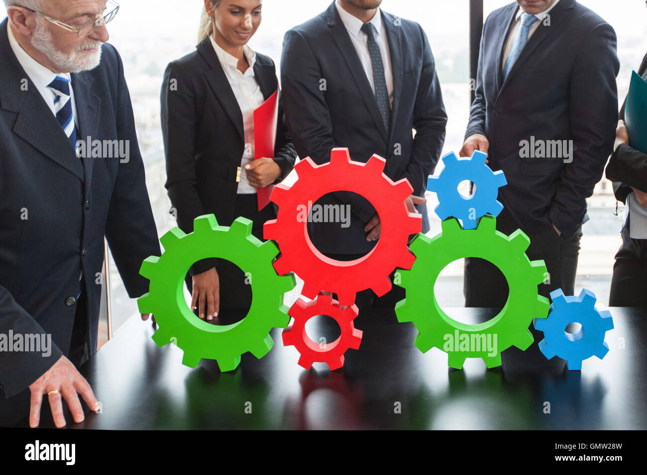 Business people assembling cogwheels, teamwork concept Stock Photo - Alamy