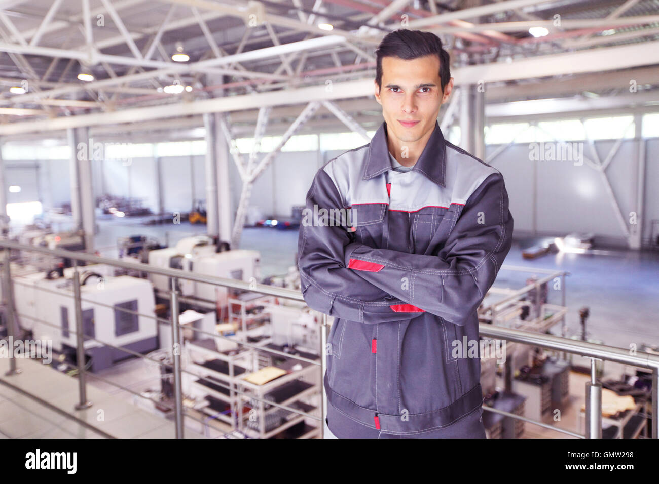 Young worker in uniform standing in CNC factory Stock Photo - Alamy