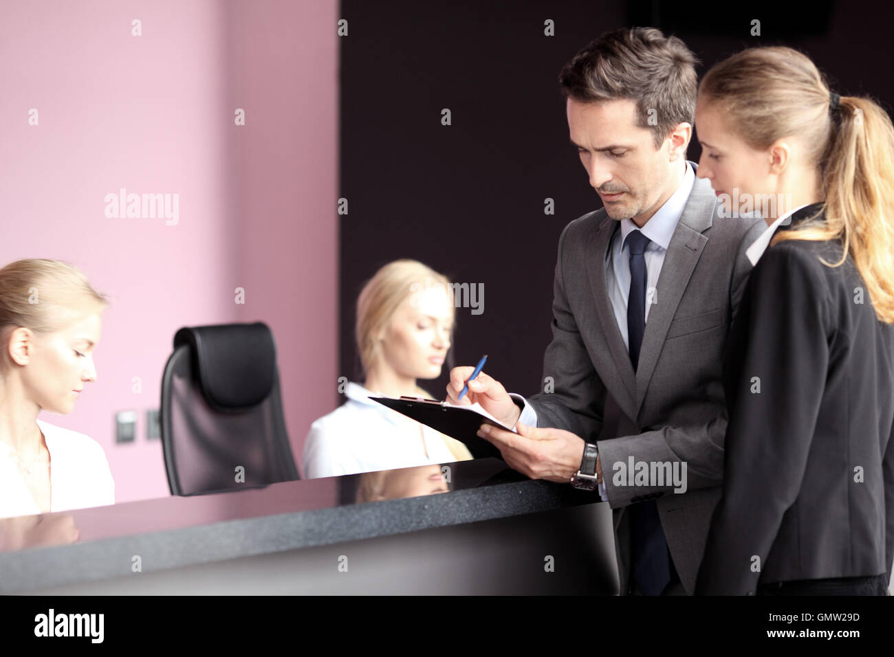 Business people filling forms at front desk Stock Photo - Alamy
