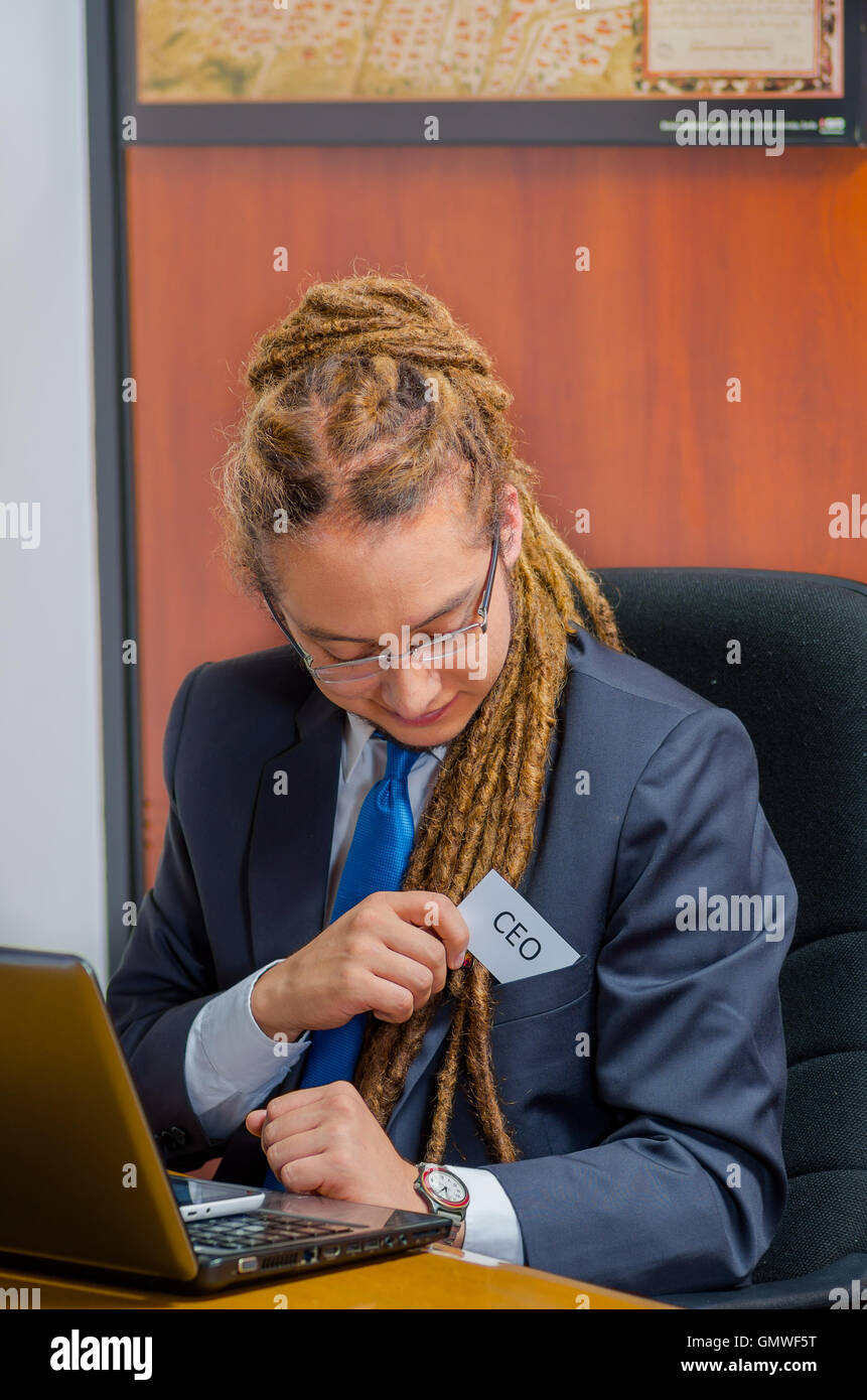 Handsome man with dreads, glasses and business suit sitting by desk ...
