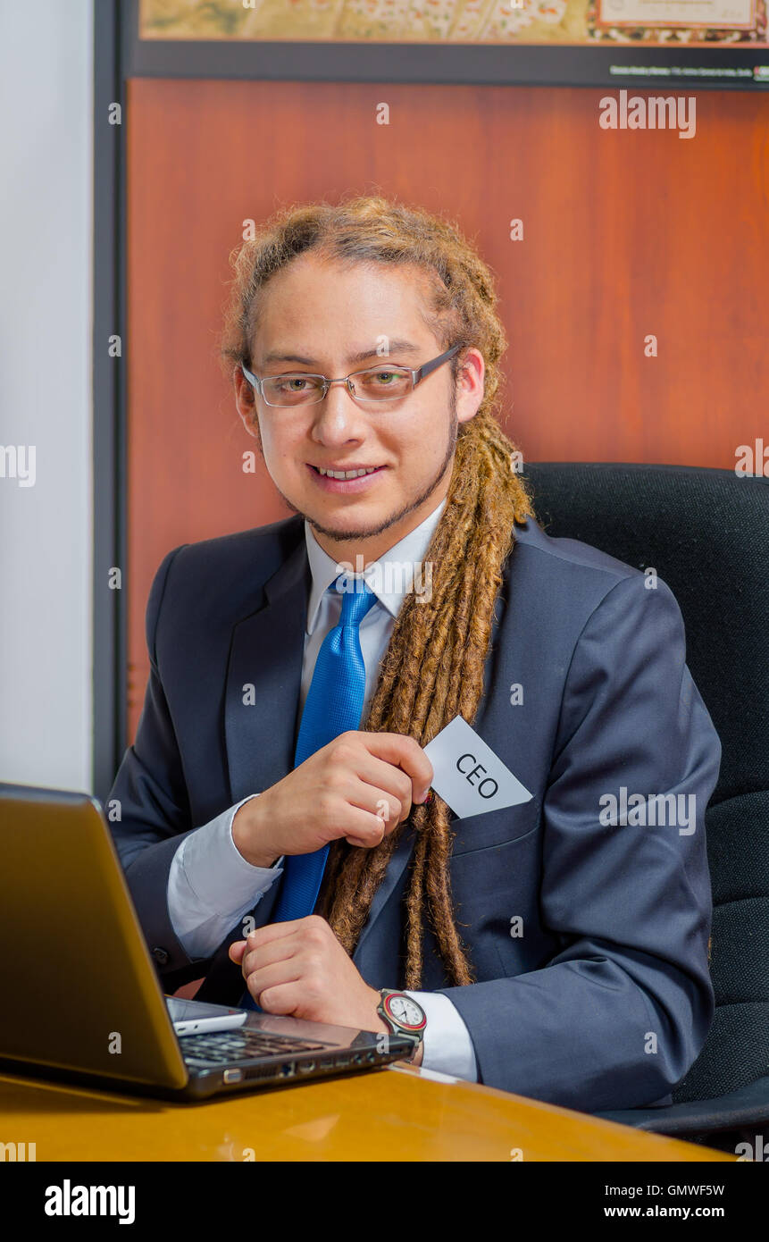 Handsome man with dreads, glasses and business suit sitting by desk ...