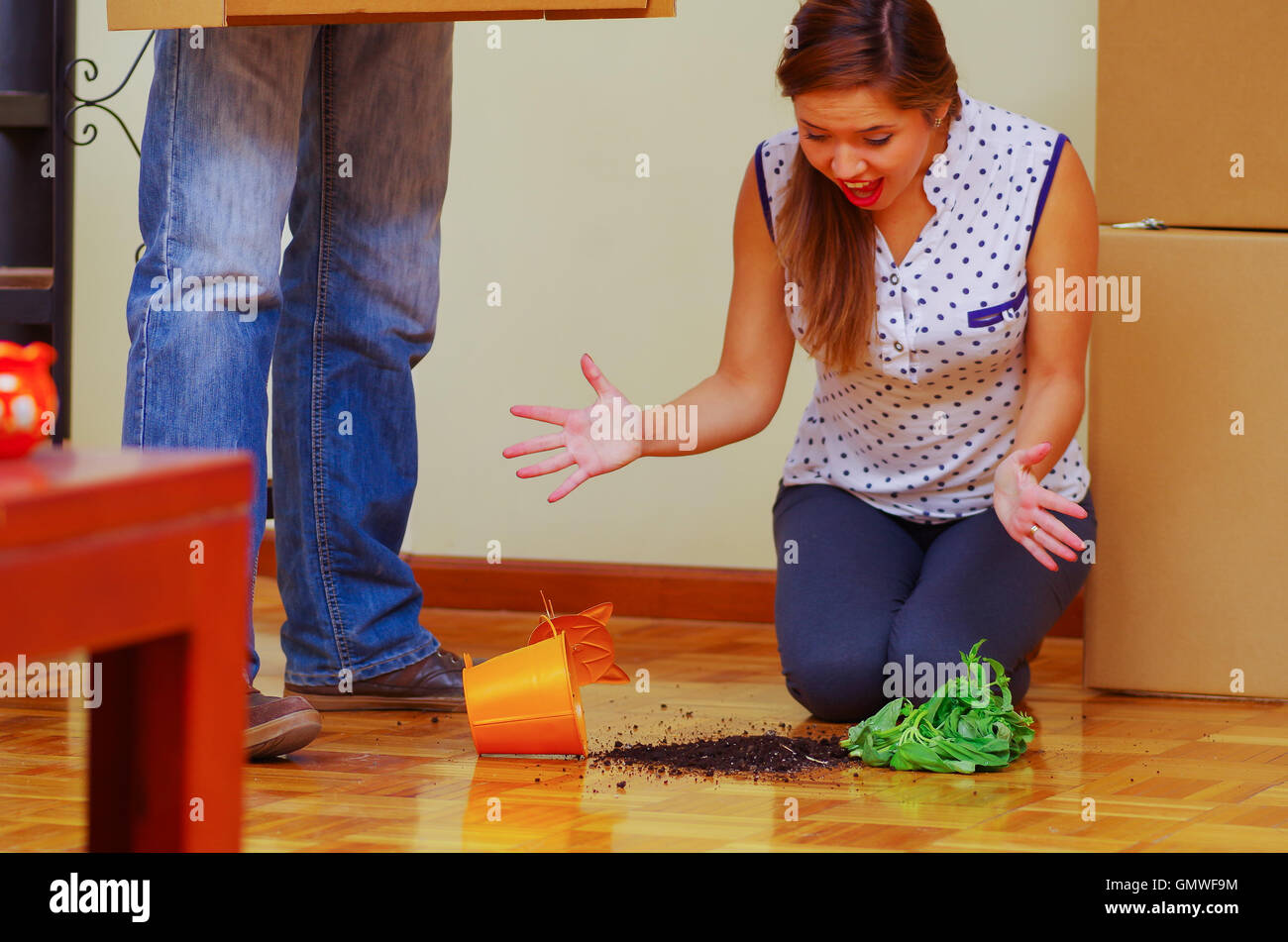 Man carrying cardboard box that has broken bottom, woman sitting ...