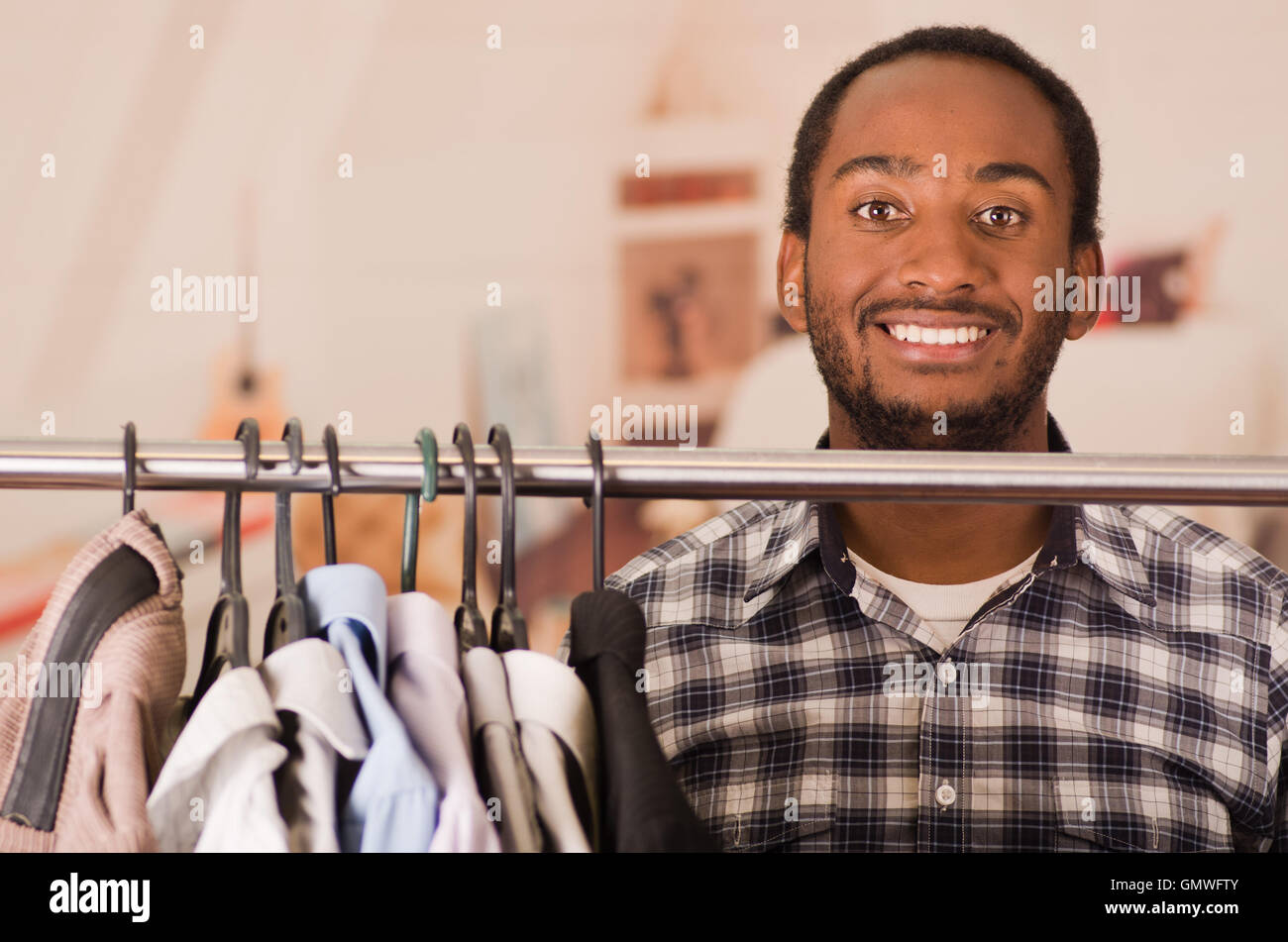 Handsome young man standing inside wardrobe going through rack of ...