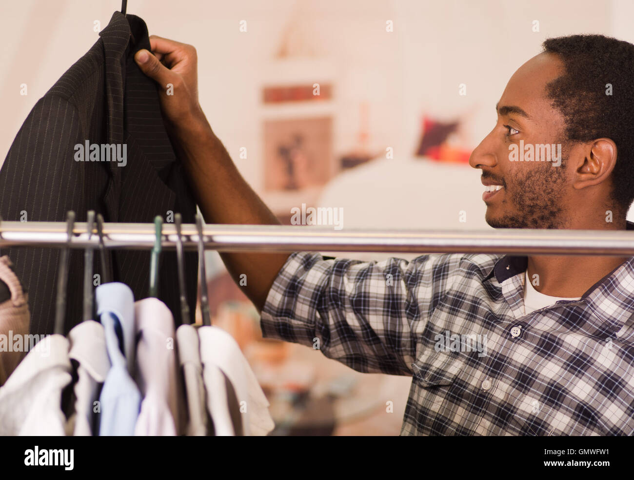 Handsome young man standing inside wardrobe going through rack of ...
