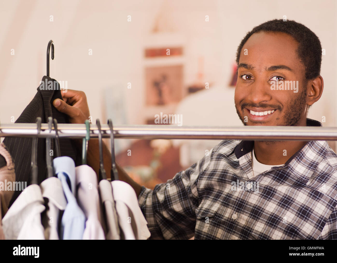 Handsome young man standing inside wardrobe going through rack of ...
