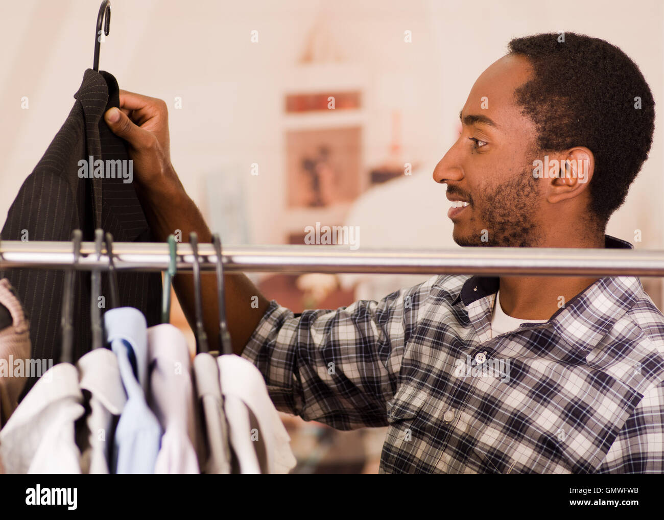 Handsome young man standing inside wardrobe going through rack of ...