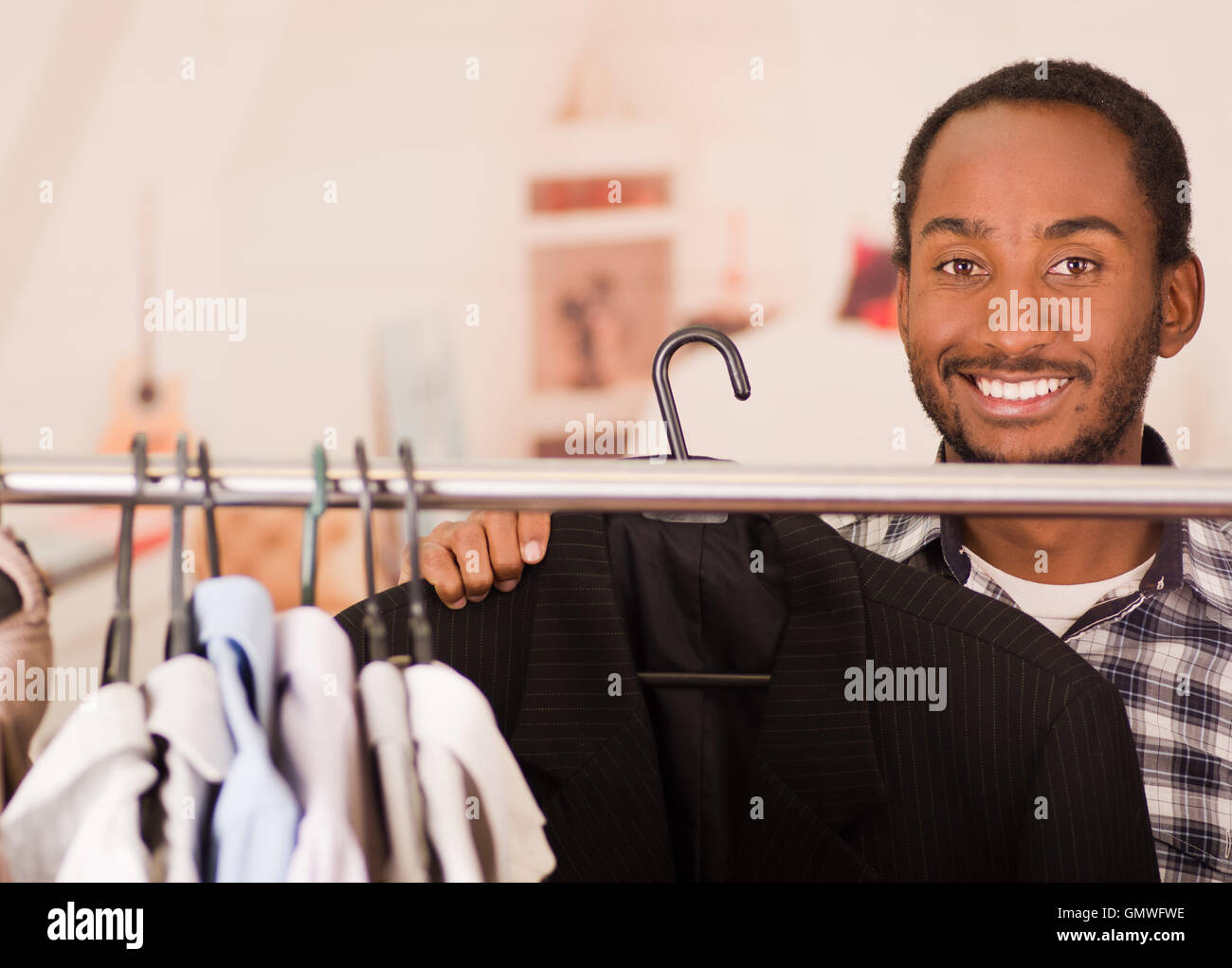 Handsome young man standing inside wardrobe going through rack of ...