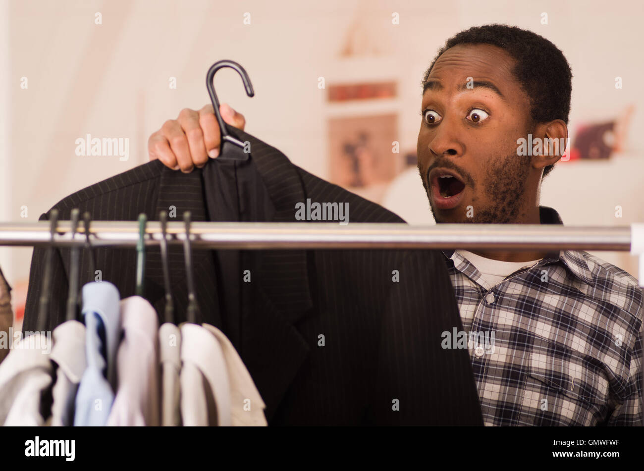 Handsome young man standing inside wardrobe going through rack of ...