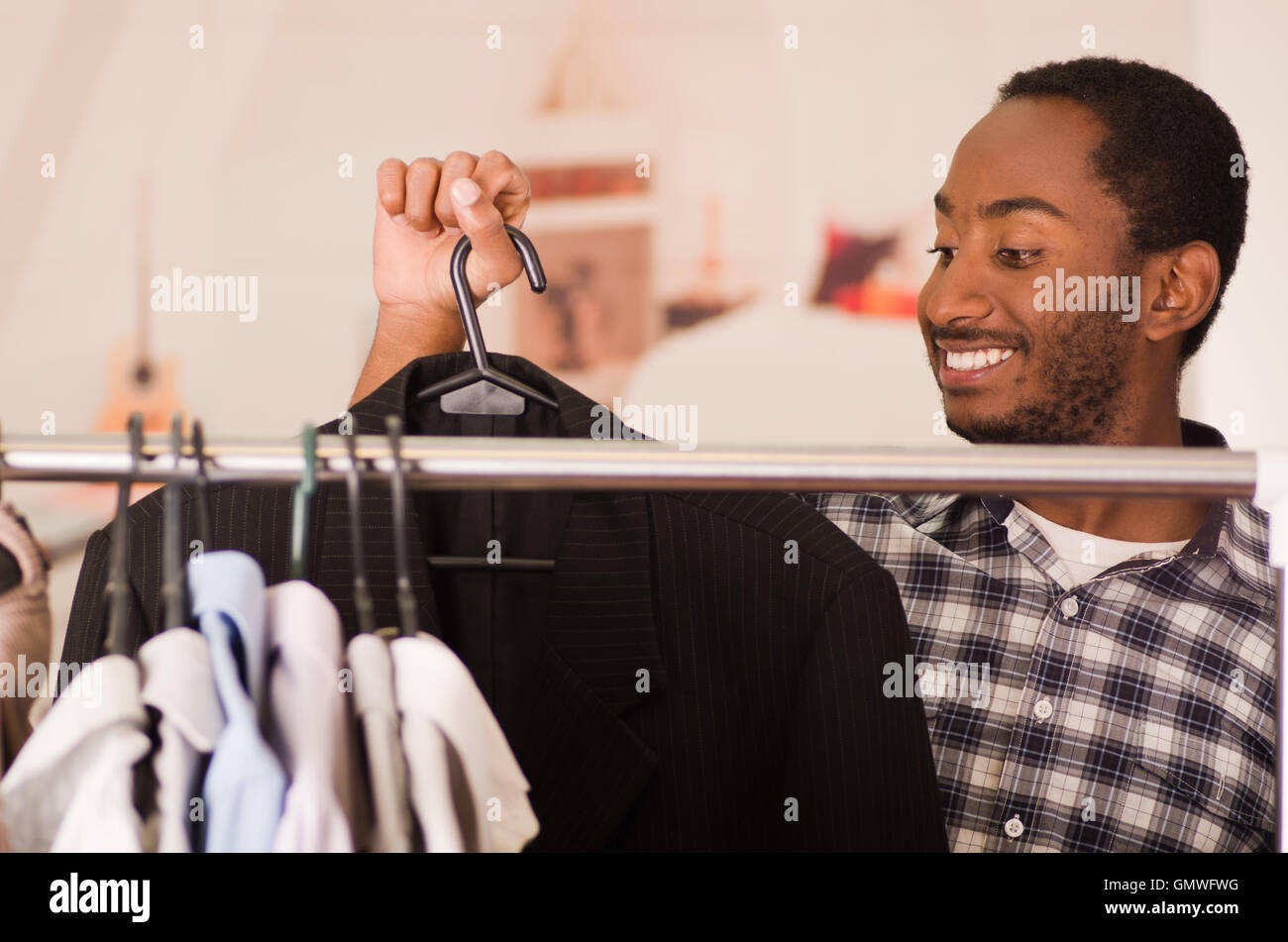 Handsome young man standing inside wardrobe going through rack of ...