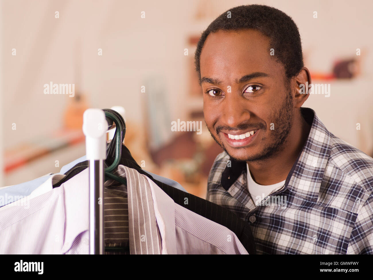 Handsome young man standing inside wardrobe going through rack of ...