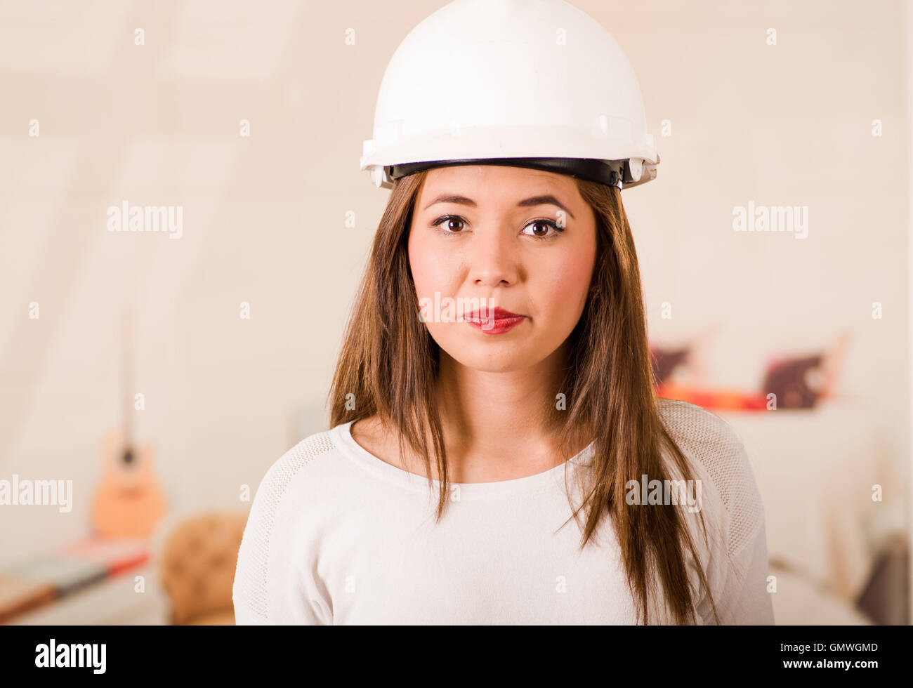 Young woman wearing construction helmet looking into camera with ...