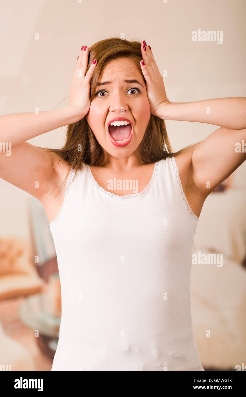 Young woman wearing white top facing camera while screaming in ...