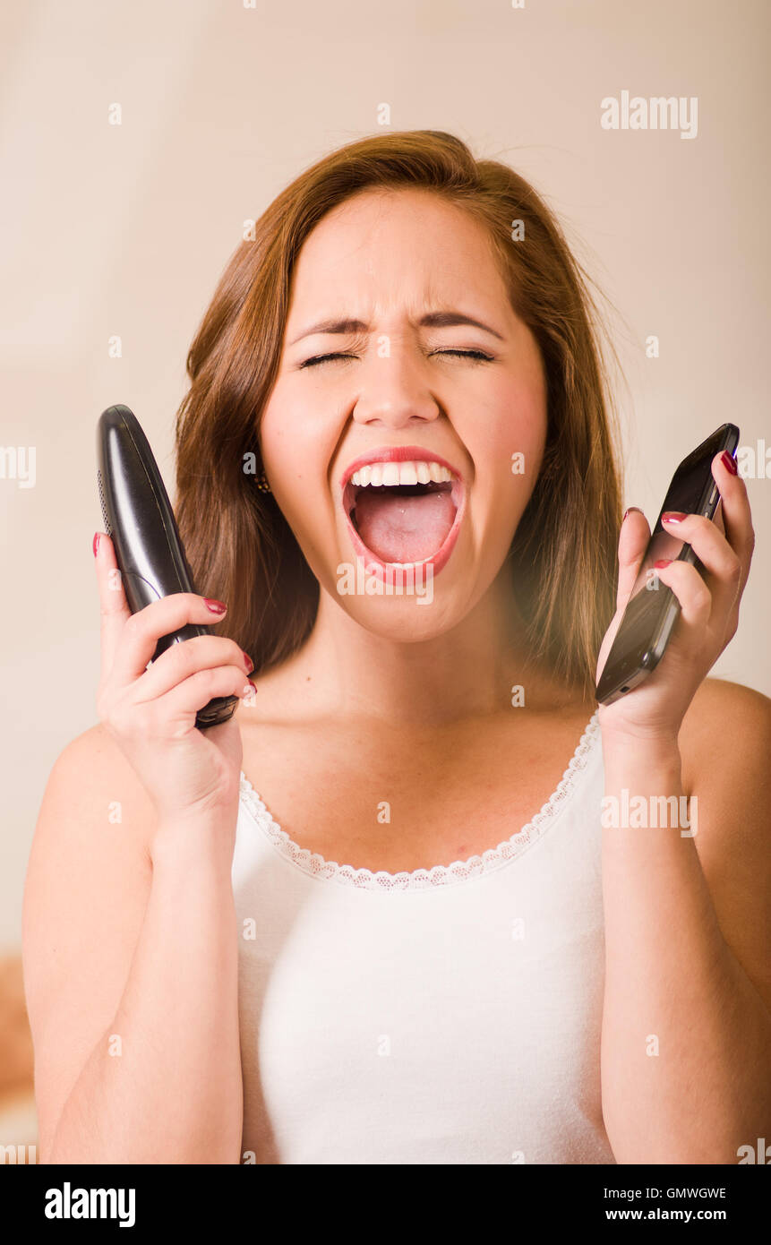 Young woman wearing white top facing camera while screaming in ...