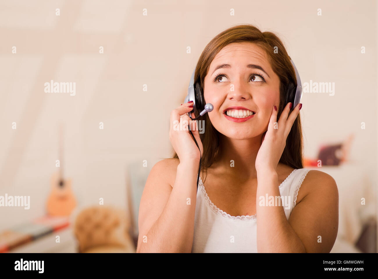 Young woman wearing white top and headset facing camera while ...