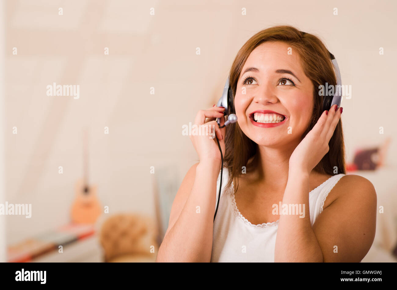 Young woman wearing white top and headset facing camera while ...