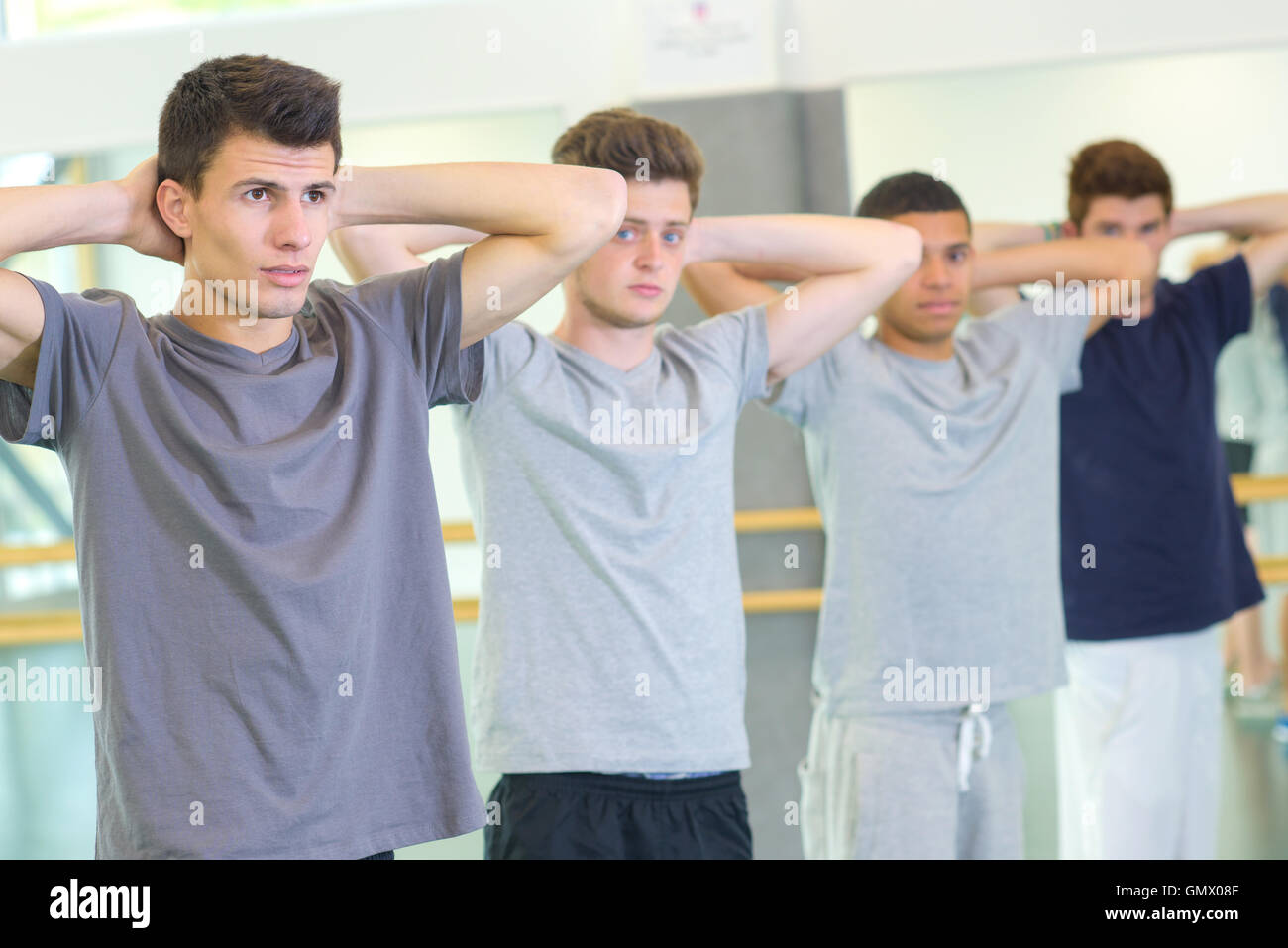 Four young men training, arms behind their heads Stock Photo - Alamy