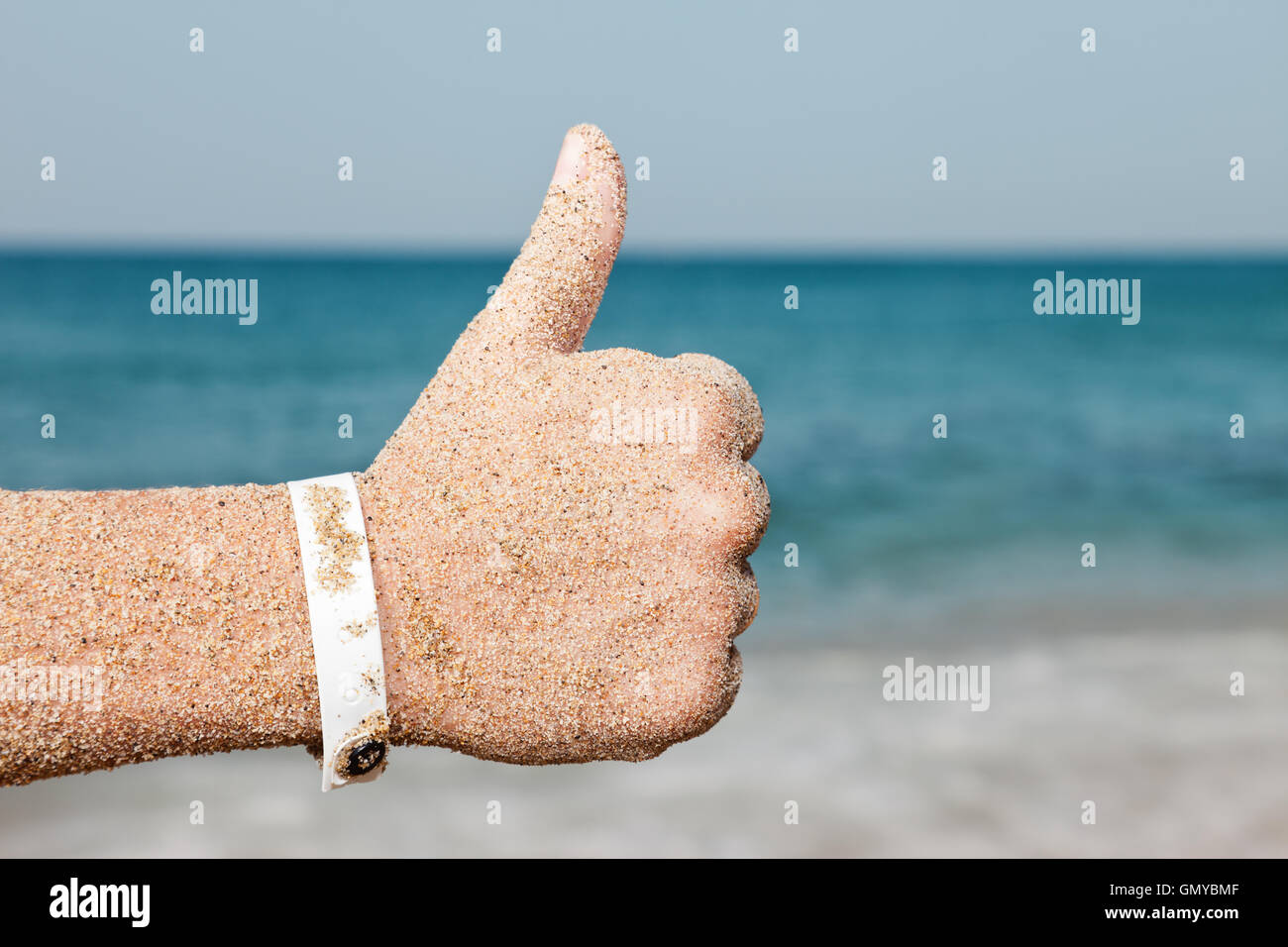 Hand gesturing thumb up on sea beach Stock Photo - Alamy