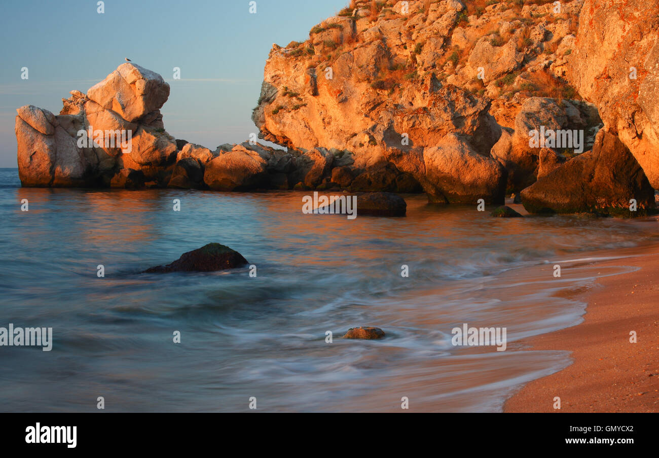 Sea beach with rocks at the sunset background Stock Photo - Alamy