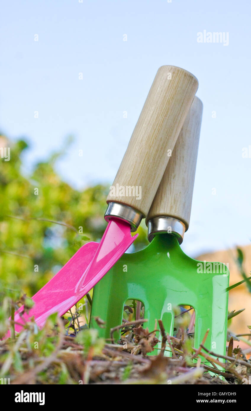 Children's spade and trowel in a garden Stock Photo - Alamy