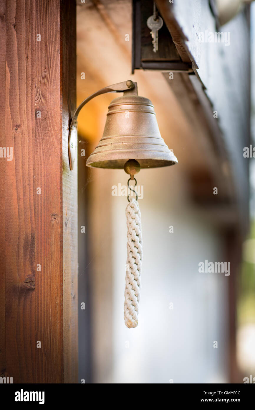 A small ship's bell with a knotted bell rope is mounted onto a wooden ...