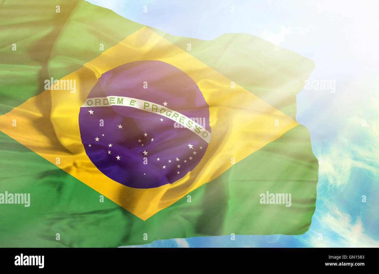 Brazil waving flag against blue sky with sunrays Stock Photo - Alamy