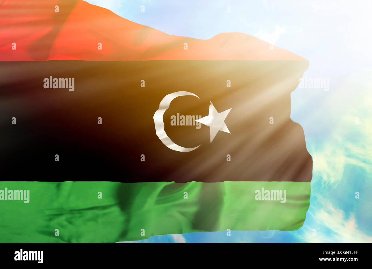 Libya waving flag against blue sky with sunrays Stock Photo - Alamy