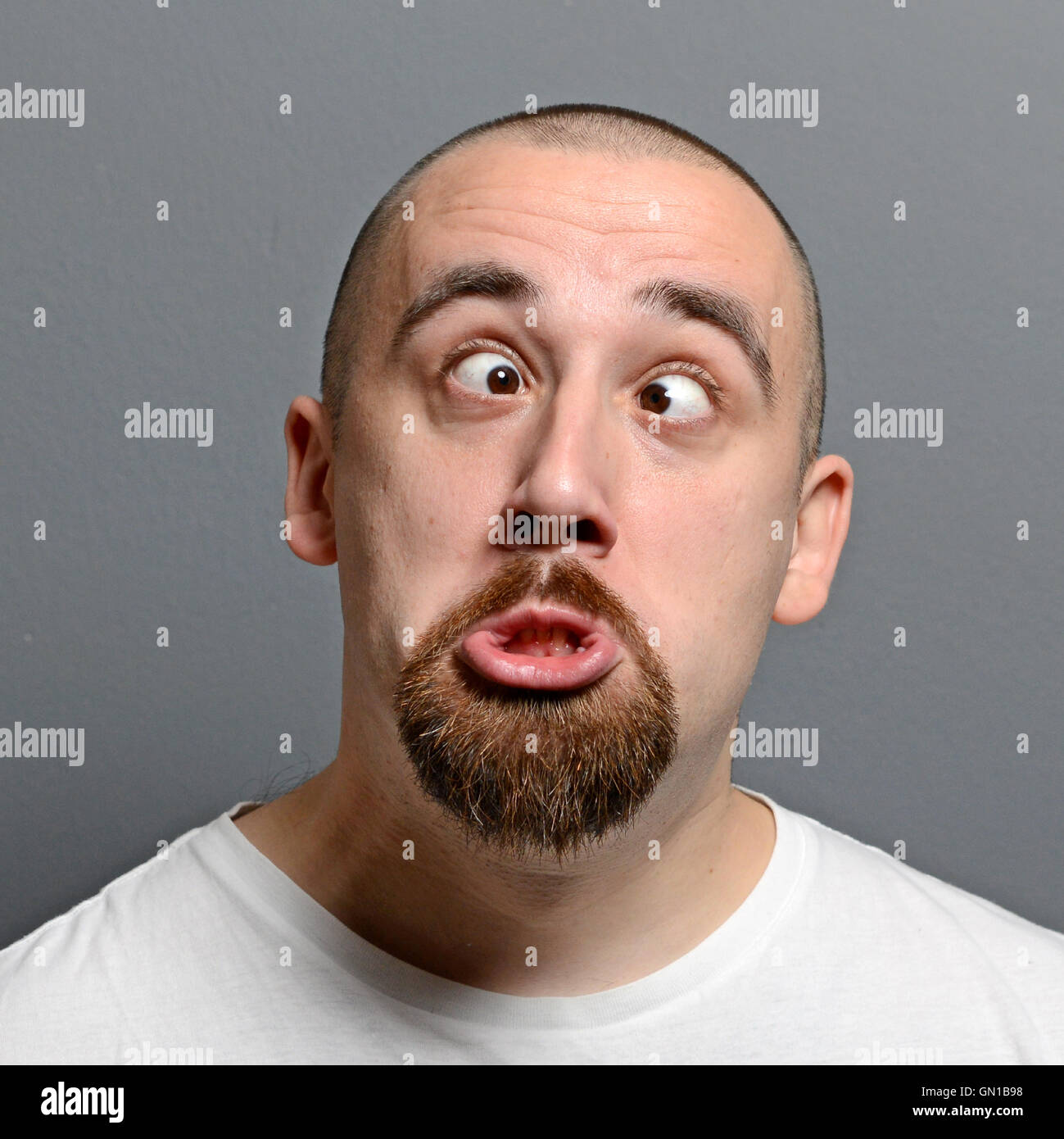 Portrait of a man making funny face against gray background Stock Photo ...