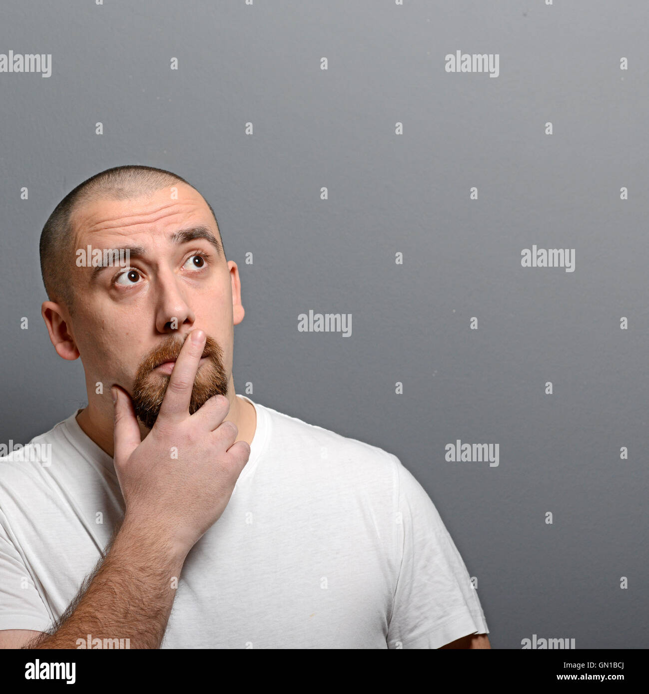 Portrait of a man thinking and looking above against gray background ...