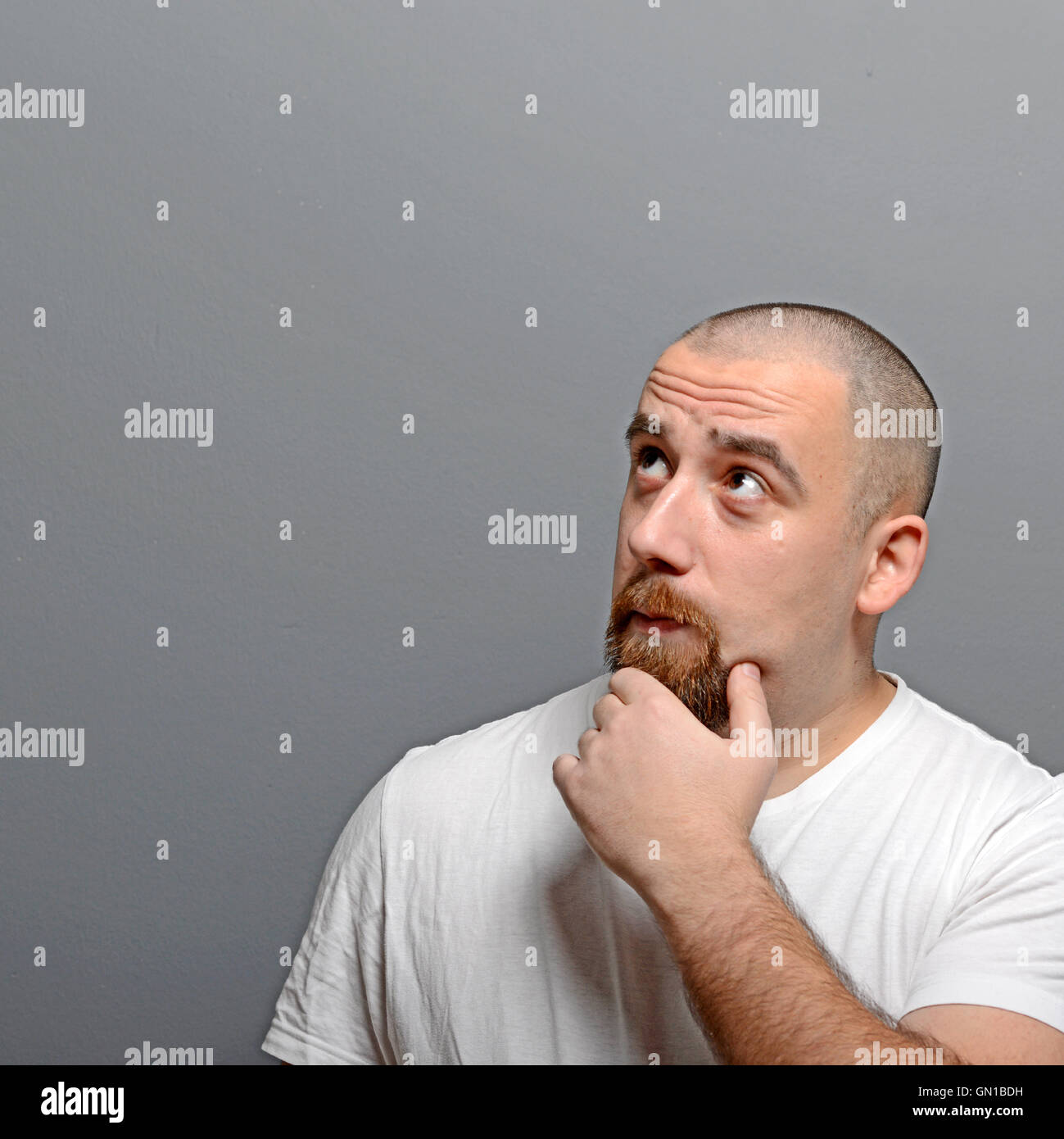 Portrait of a man thinking and looking above against gray background ...