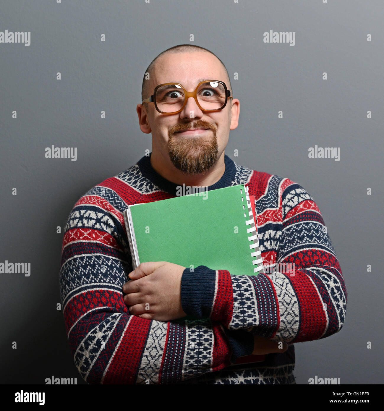 Portrait of a nerd holding book with retro glasses against gray ...