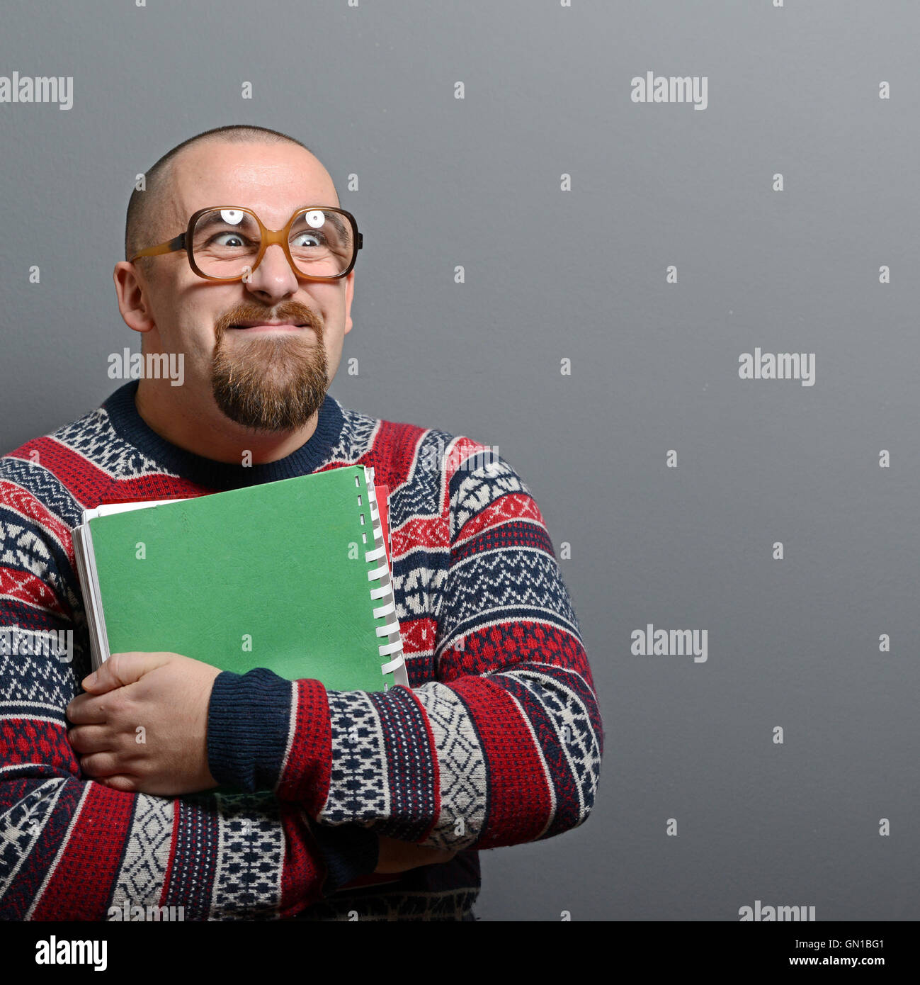 Portrait of a nerd holding book with retro glasses against gray ...