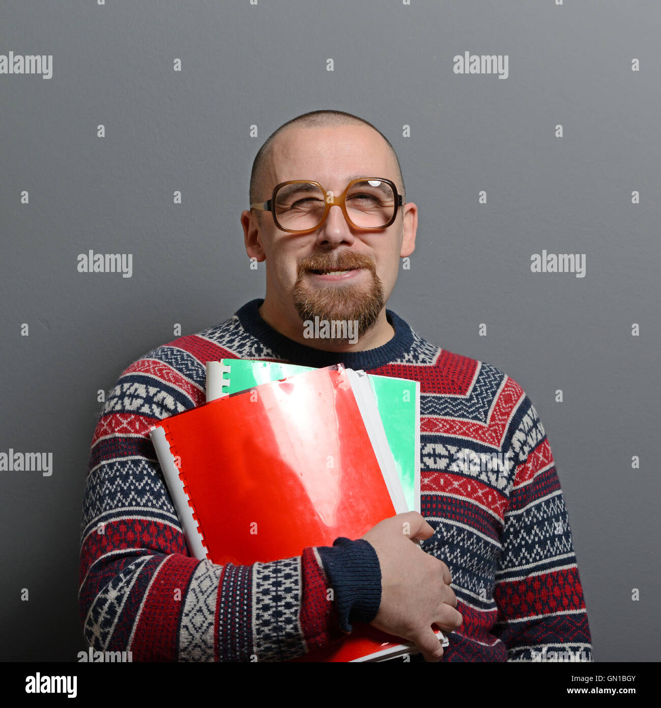 Portrait of a nerd holding book with retro glasses against gray ...