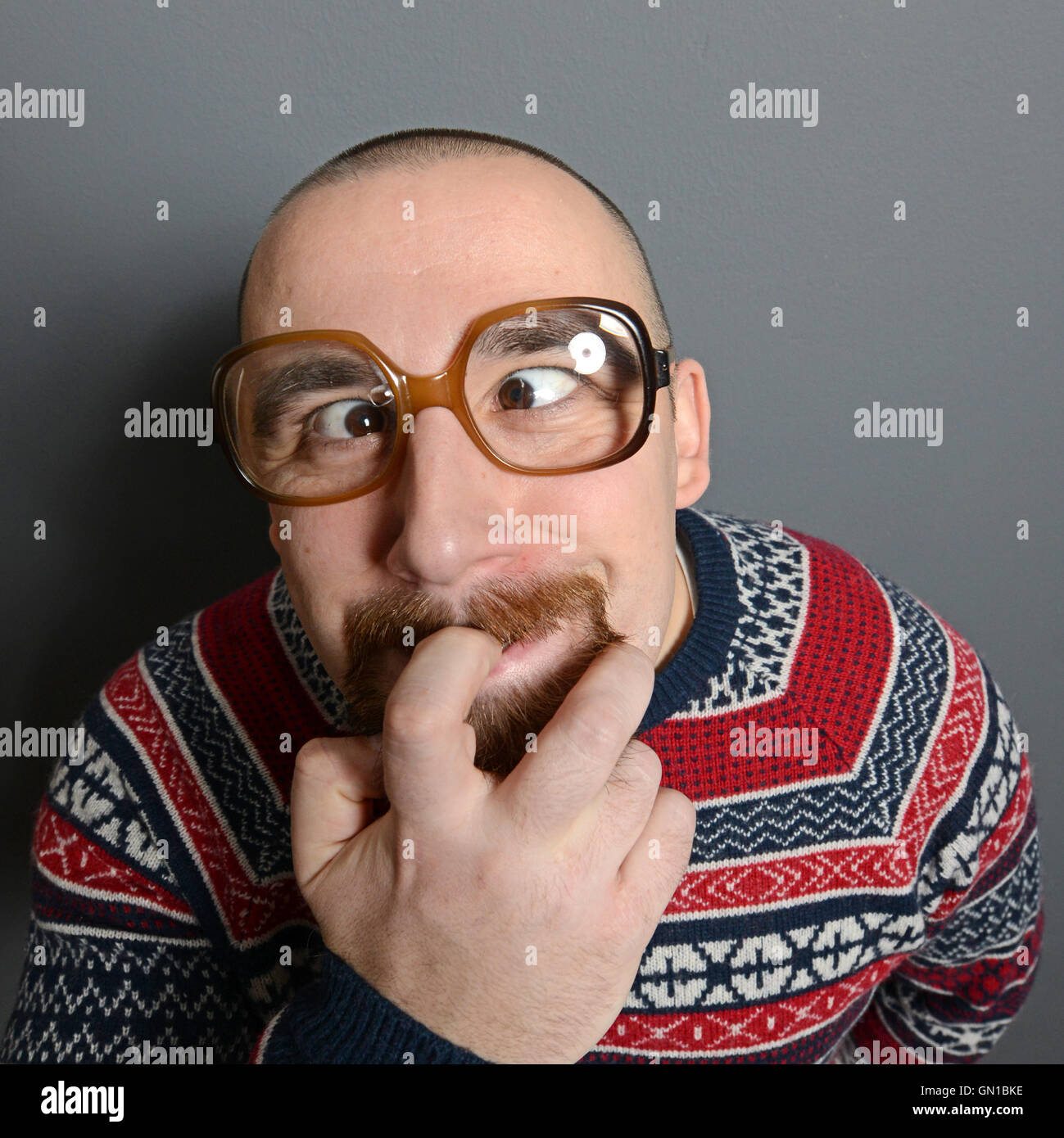 Portrait of a nerd with glasses and retro sweater against gray ...