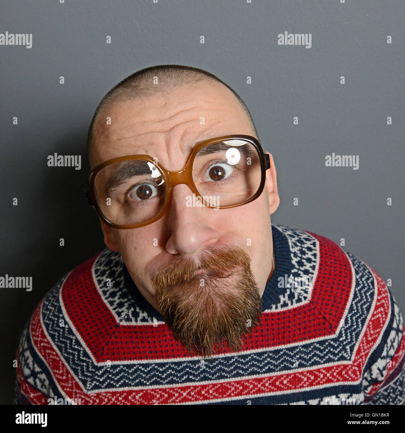 Portrait of a nerd with glasses and retro sweater against gray ...