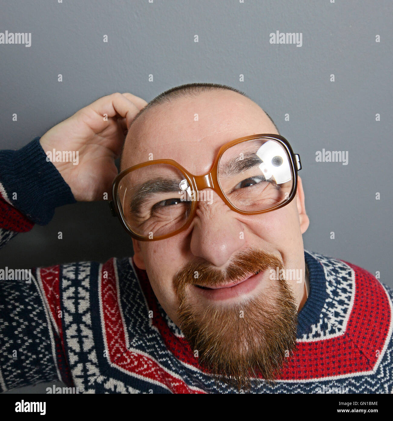 Portrait of a nerd with glasses and retro sweater against gray ...