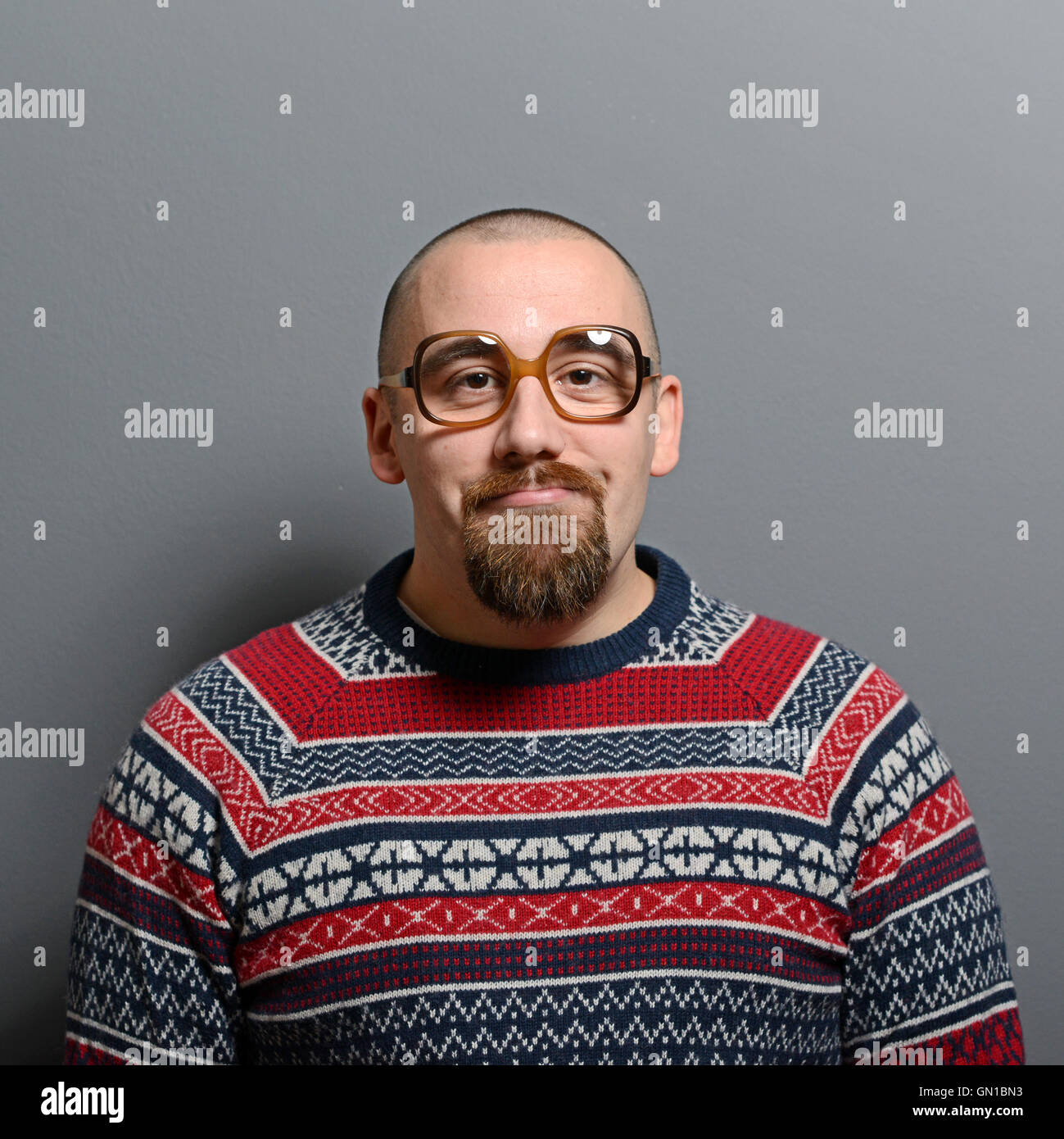 Portrait of a nerd with glasses and retro sweater against gray ...