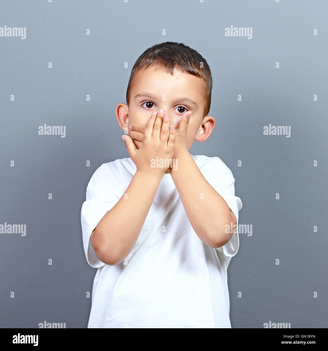 Cute little boy kid covering his face with hands against gray ...