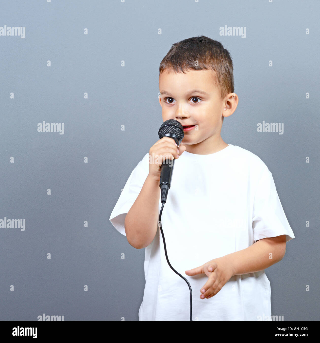 Cute little boy kid singing on microphone against gray background Stock ...