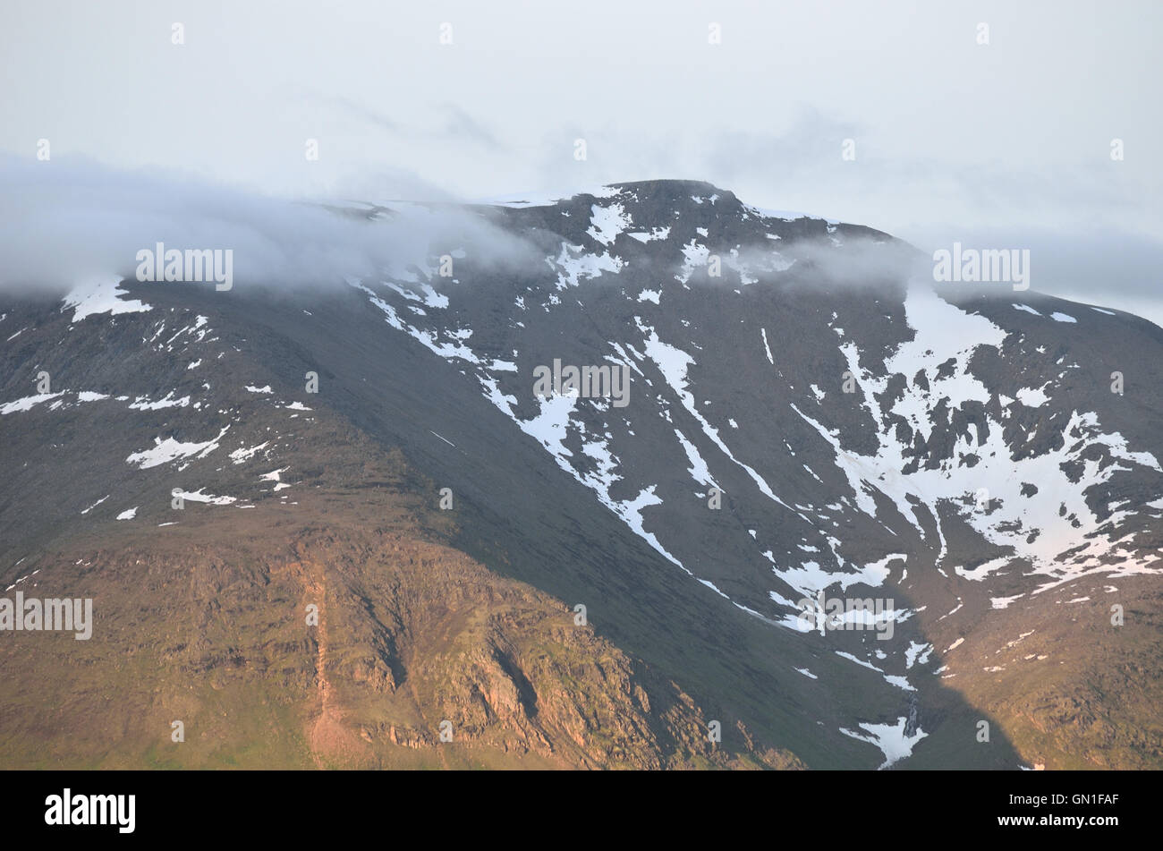 mighty mountain peak with clouds and snow patches in summer Stock Photo ...
