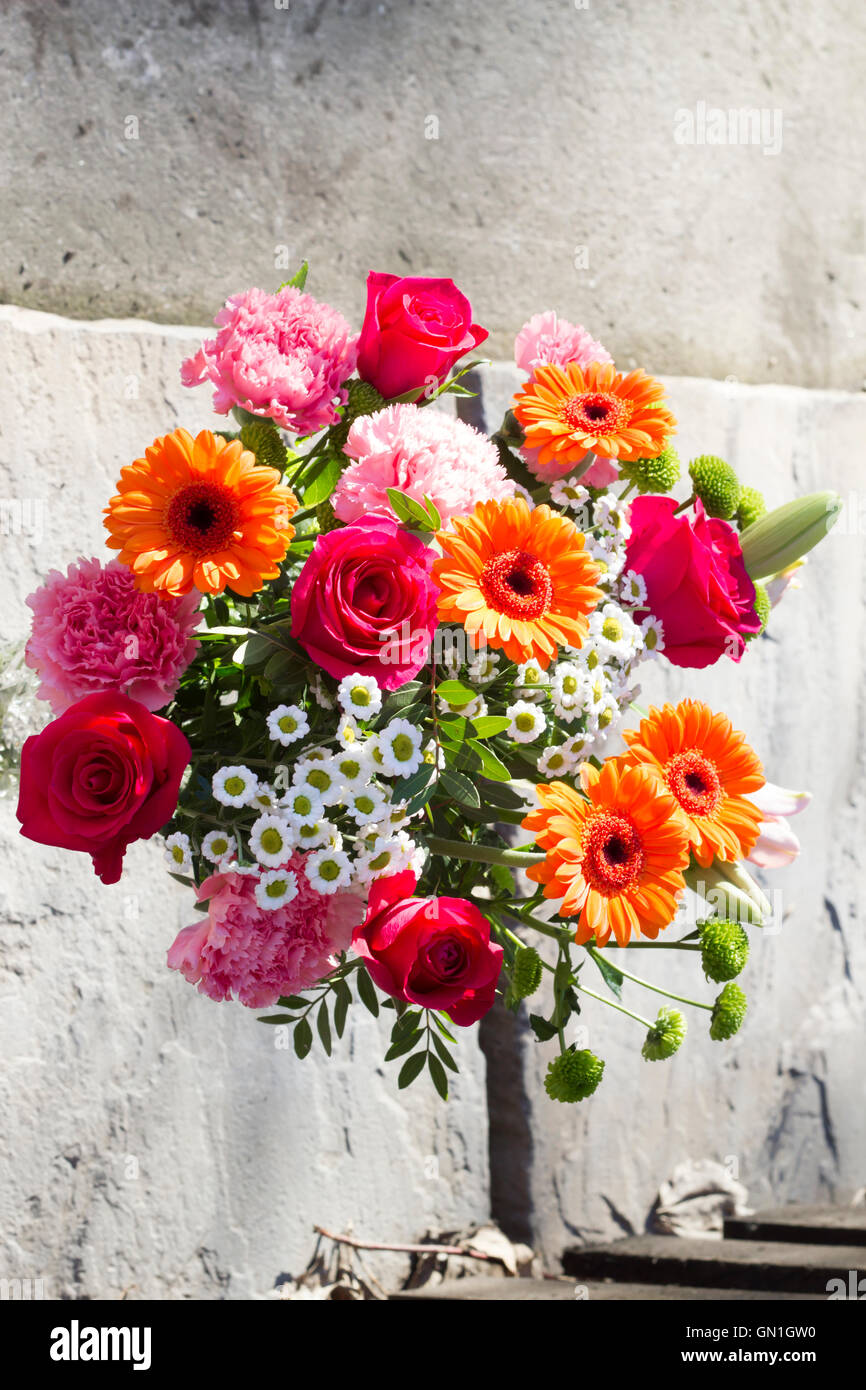 Bouquet of various bright, colorful flowers outside with Grey stone ...