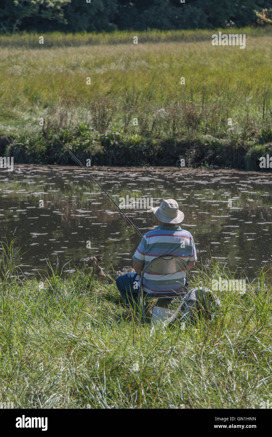 Fisherman / angler seated beside river in the Autumn sunshine Stock ...