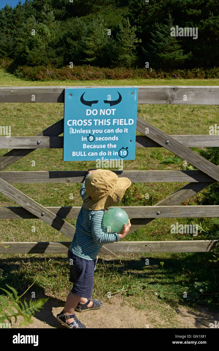 Toddler by "Beware of the Bull" sign on farm gate Stock Photo - Alamy
