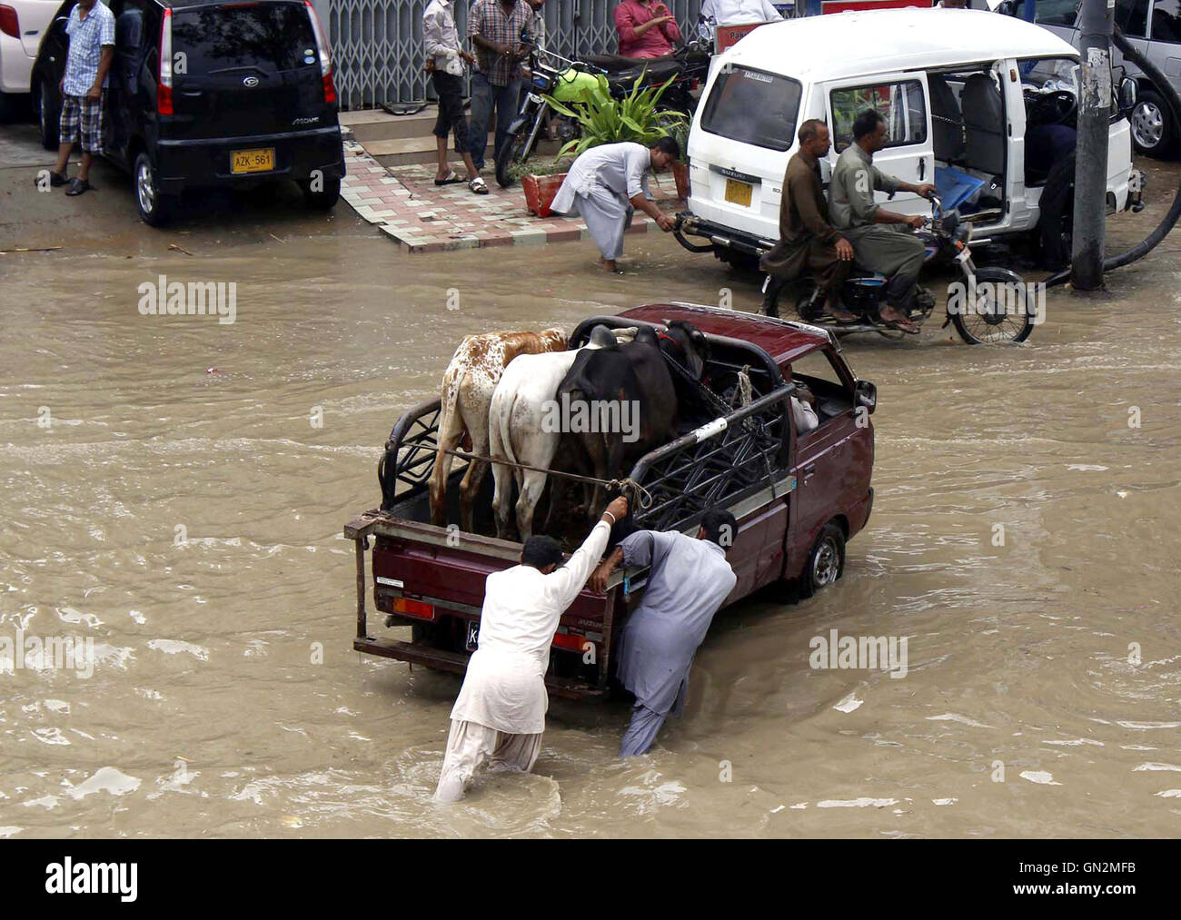 Karachi. 27th Aug, 2016. Pakistanis push a vehicle in floodwater after ...