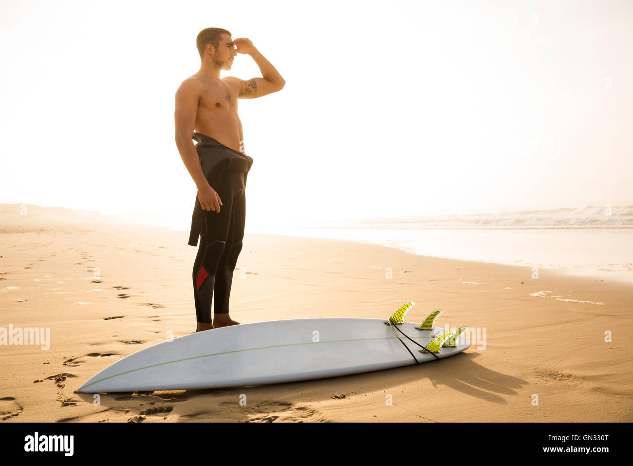 A surfer with his surfboard looking to the waves Stock Photo - Alamy