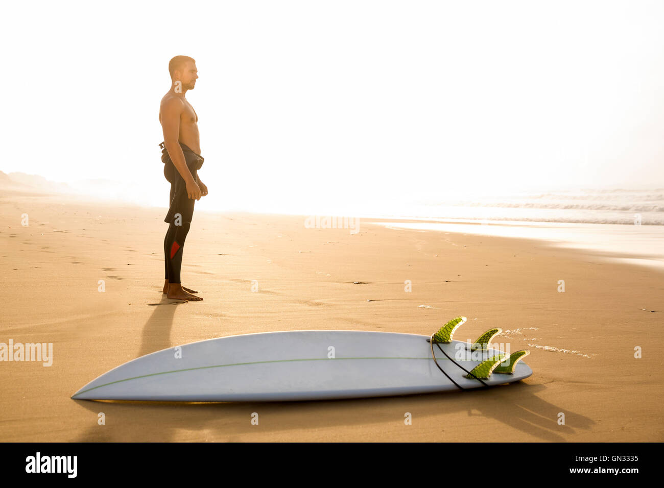 A surfer with his surfboard at the beach Stock Photo - Alamy