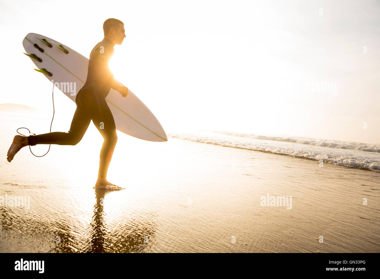 A surfer with his surfboard running to the waves Stock Photo - Alamy